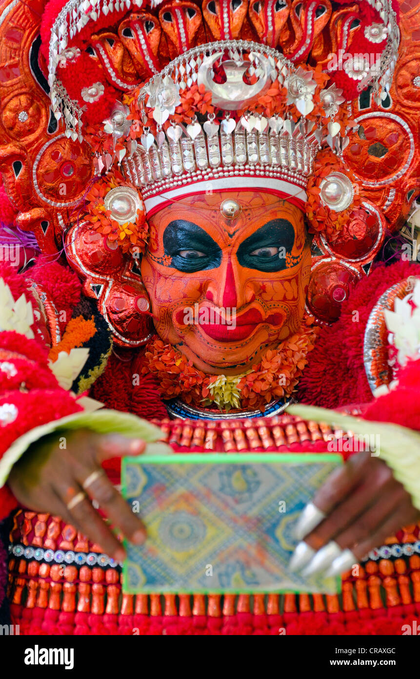 Performer wearing colourful make-up preparing for the Theyyam ceremony ...