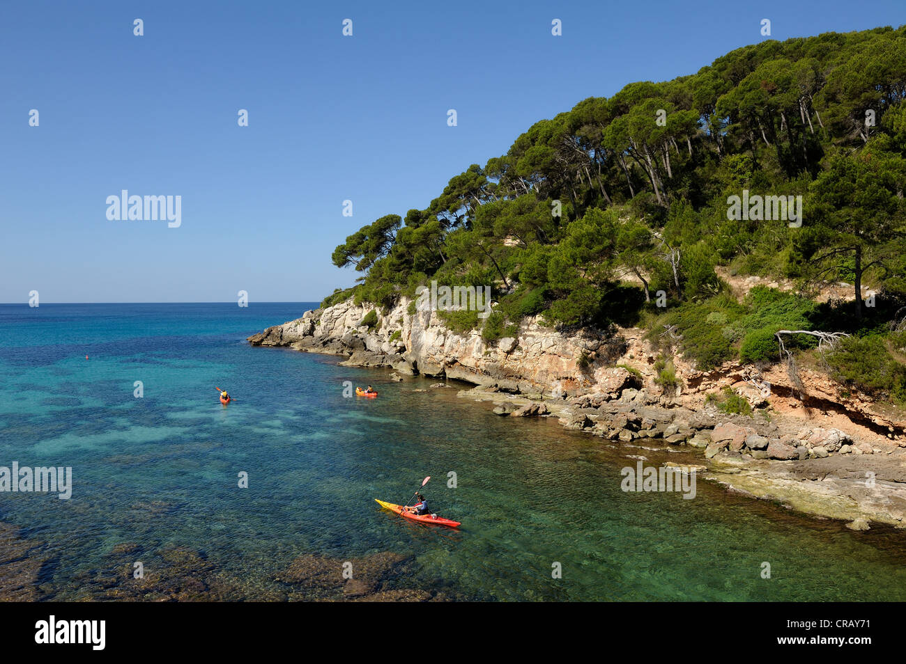 group of tourists kayaking in the clear waters of cala santa galdana ...