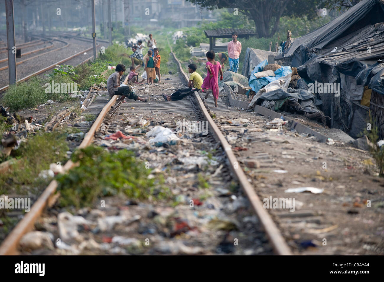 Slum huts with children playing alongside the railway line, Shibpur ...