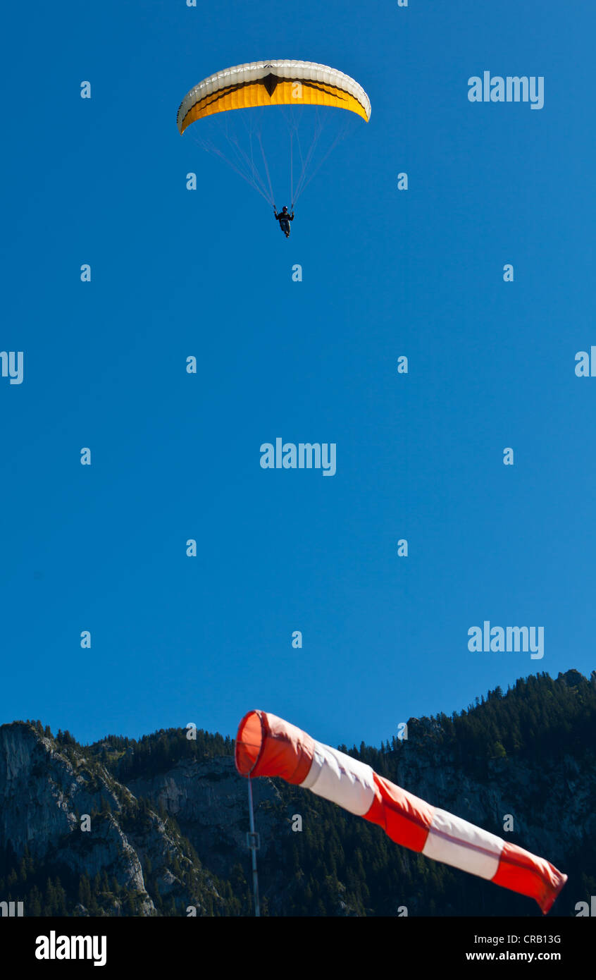 Paraglider landing against the wind with a windsock, in front of ...