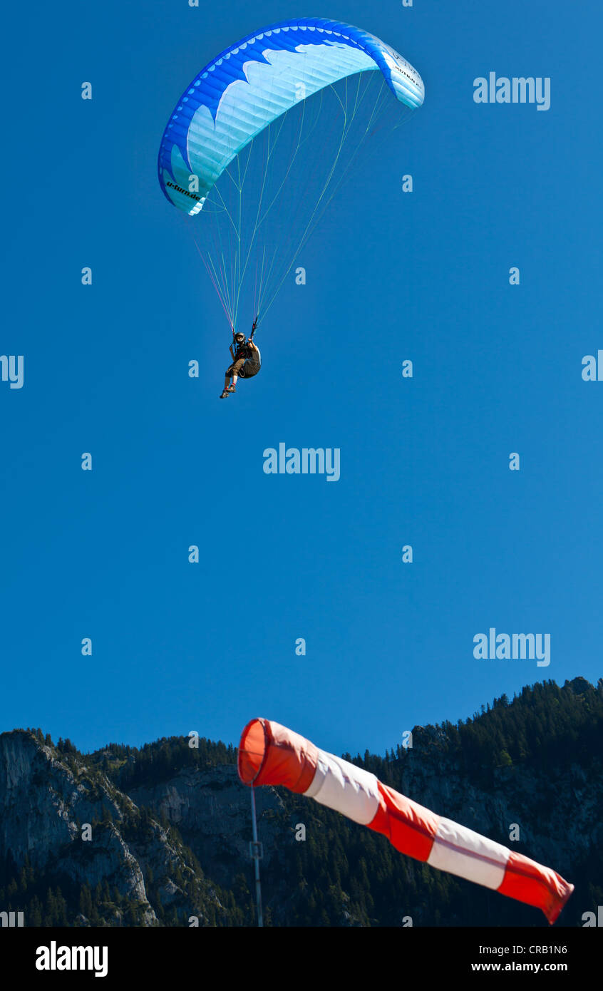 Paraglider, landing approach, upwind, a windsock in the foreground ...