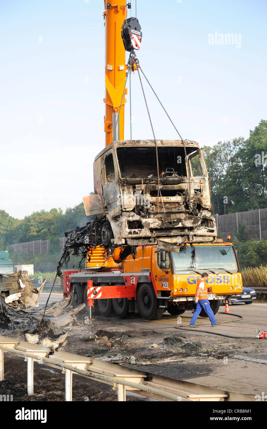 A burned-out truck engine being salvaged by a crane on the A8 motorway ...