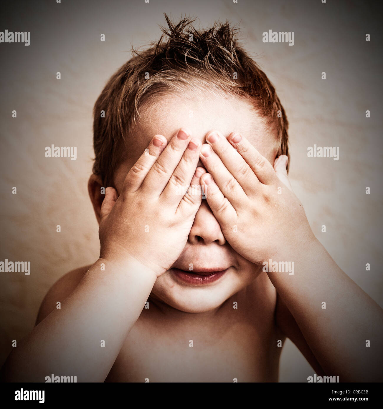 Portrait of little boy closed eyes with his hands, studio shot Stock ...
