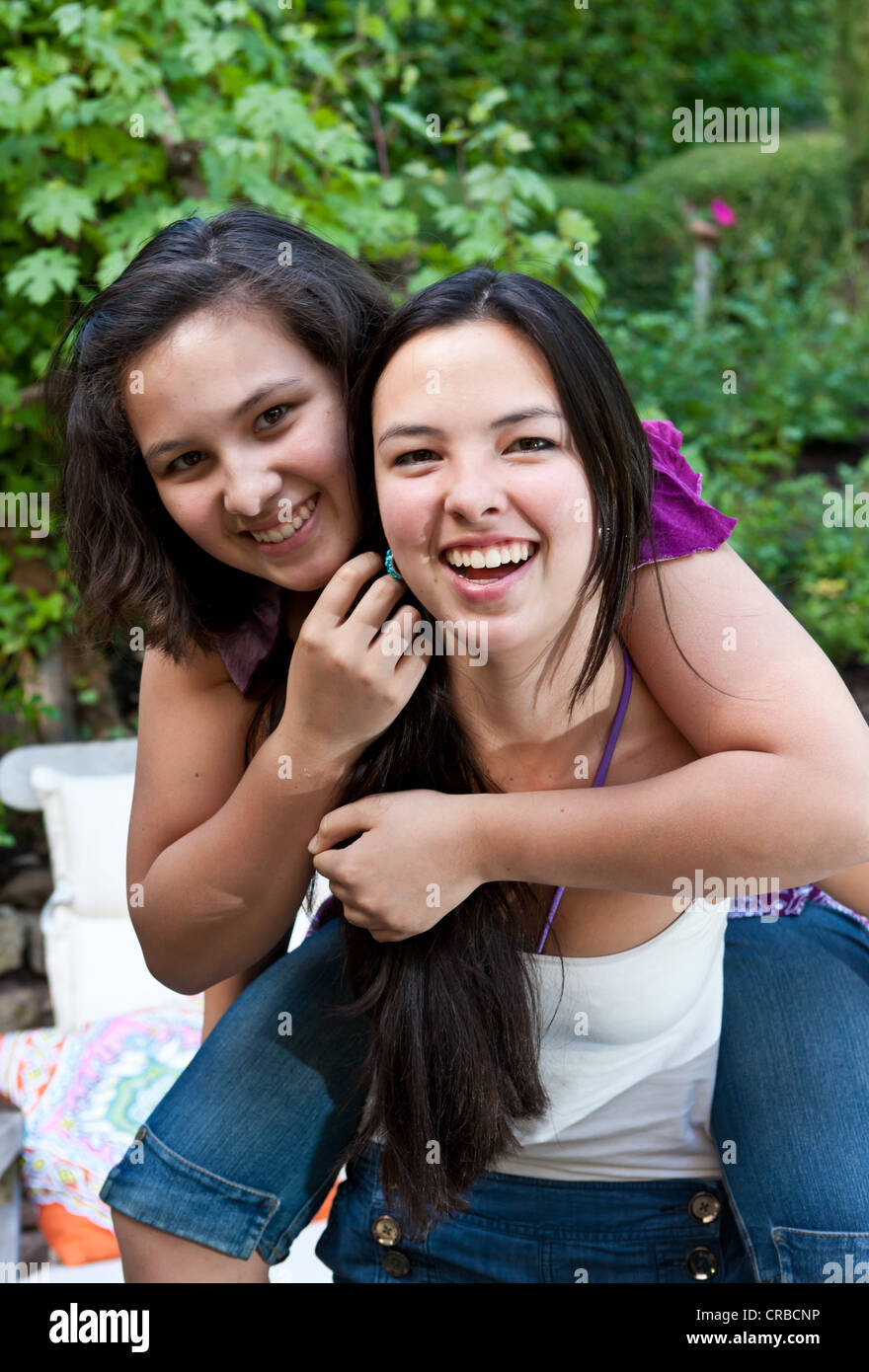Two girls, about 13 years and 18 years, one with the other piggyback ...