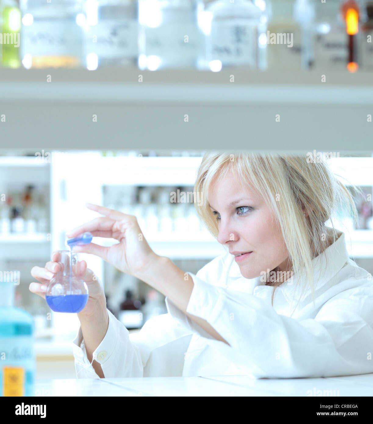 Closeup of a female researcher holding up a test tube and a retort and ...