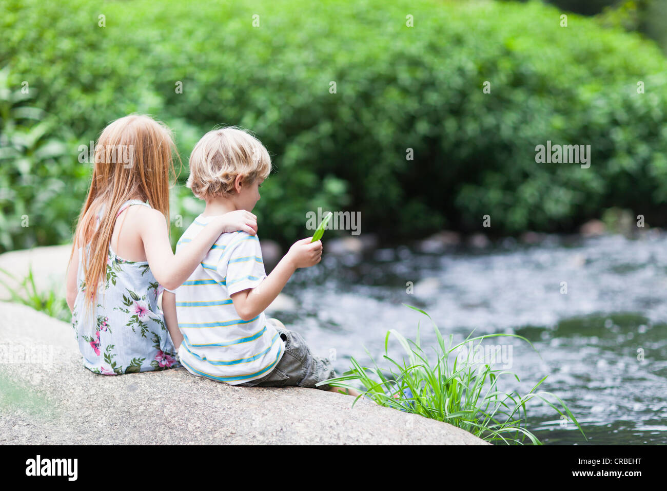 Children sitting on rock together Stock Photo - Alamy