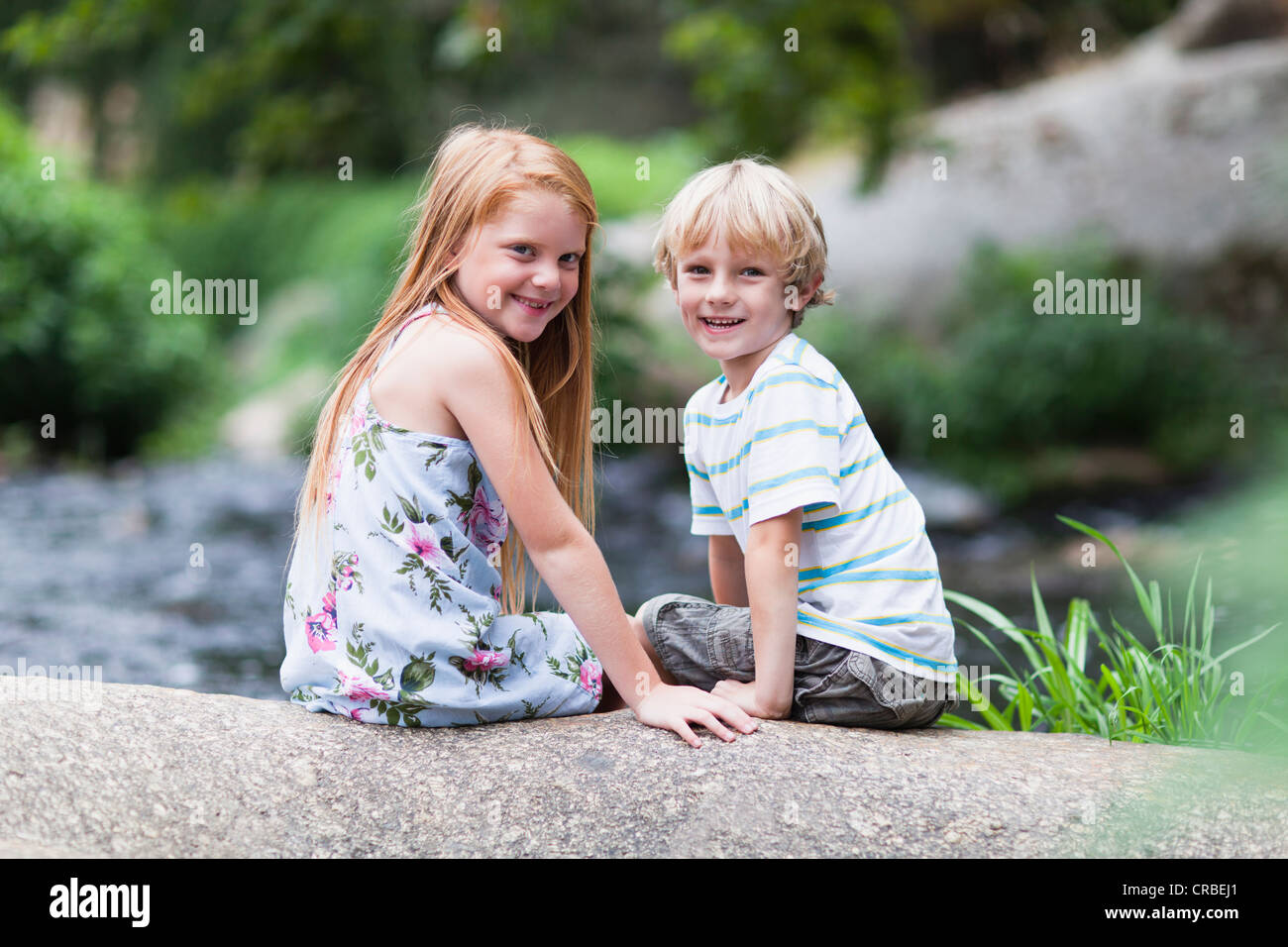 Children sitting on rock together Stock Photo - Alamy