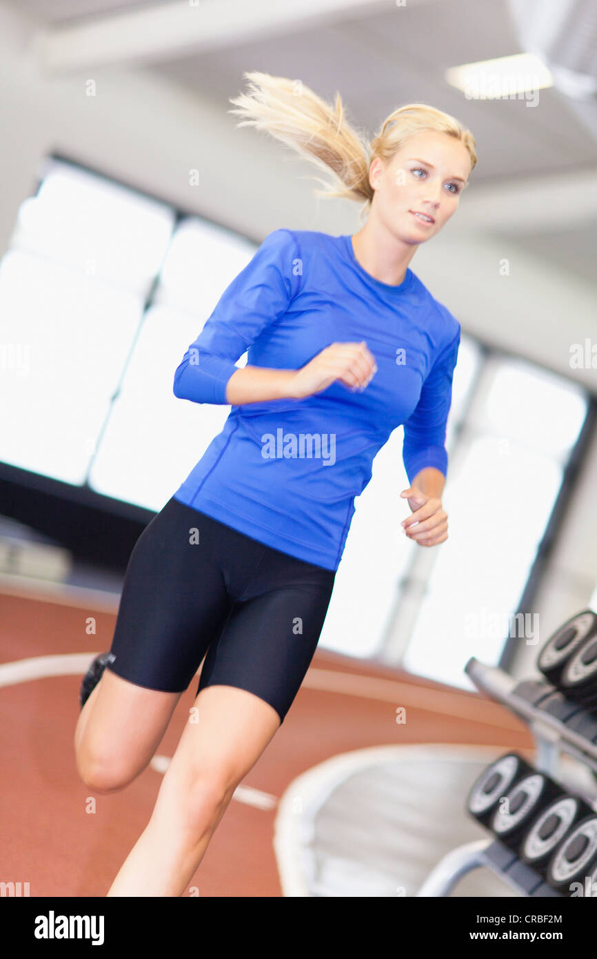 Woman running on indoor track in gym Stock Photo - Alamy