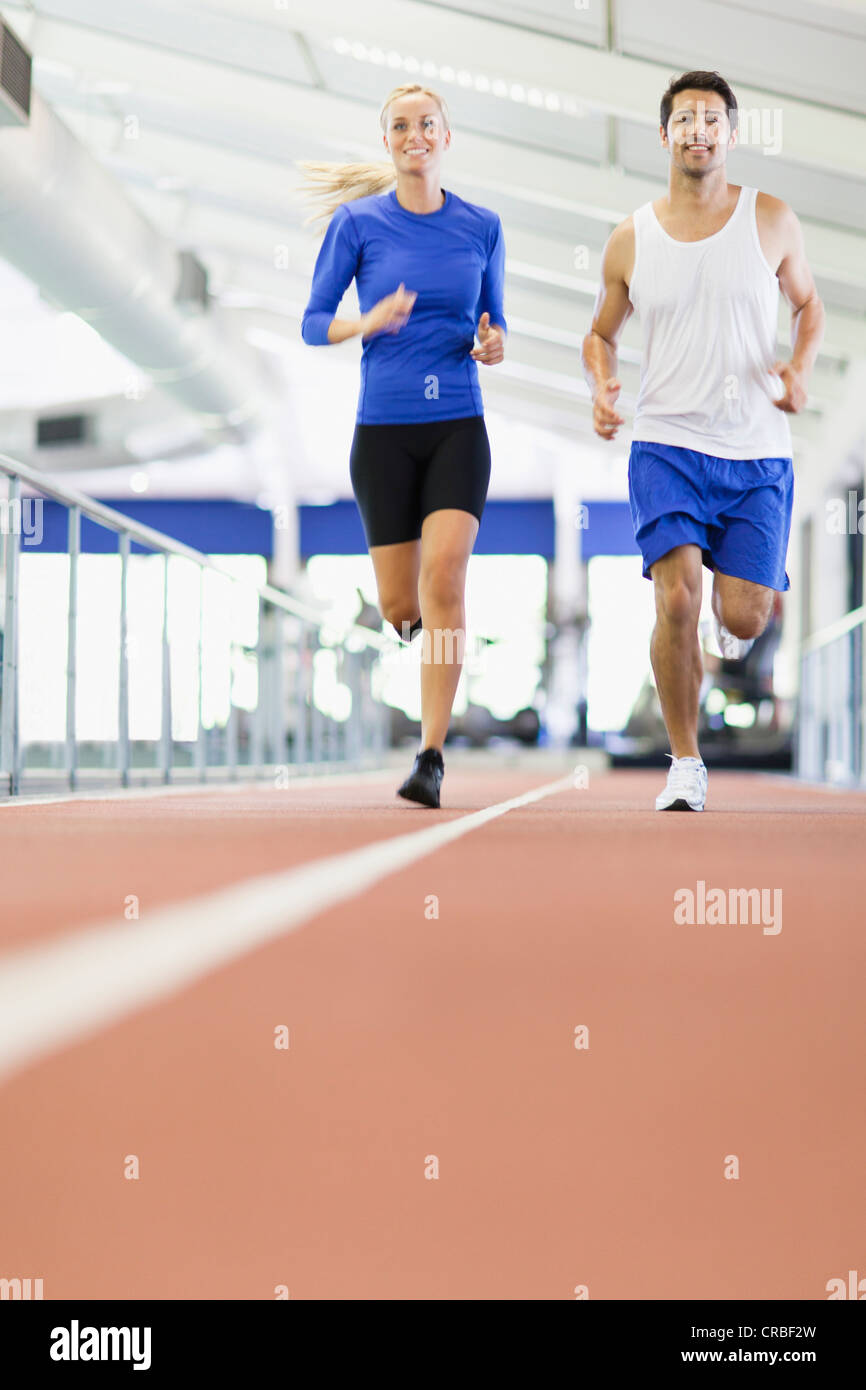 Couple running on indoor track in gym Stock Photo - Alamy