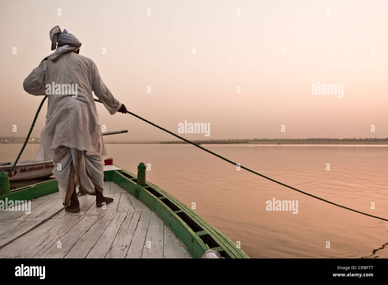 An Indian man pulls a rope on a boat on the Ganges in Varanasi, India ...