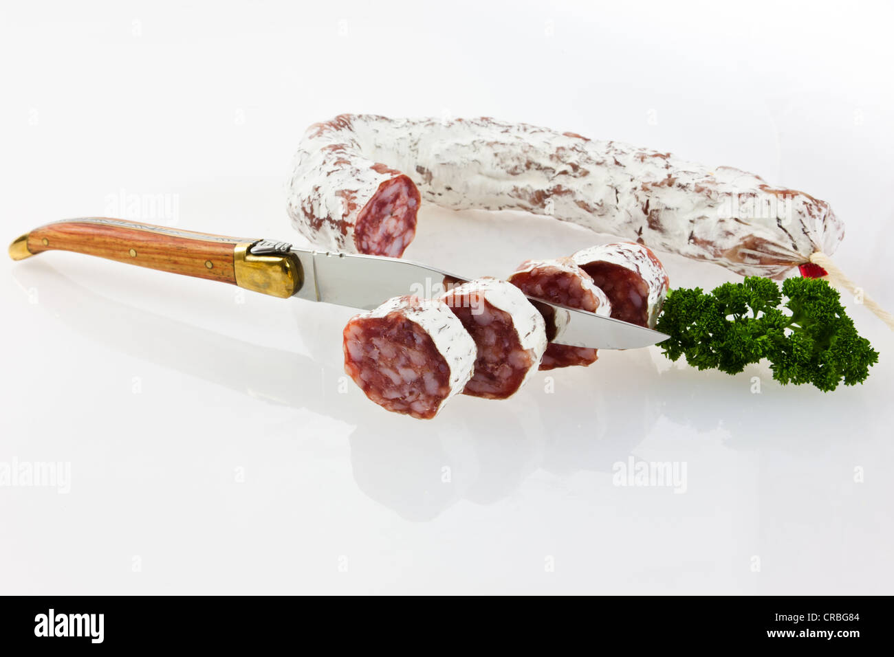 Gourmet salami, premium salami cut with knife, and parsley Stock Photo ...