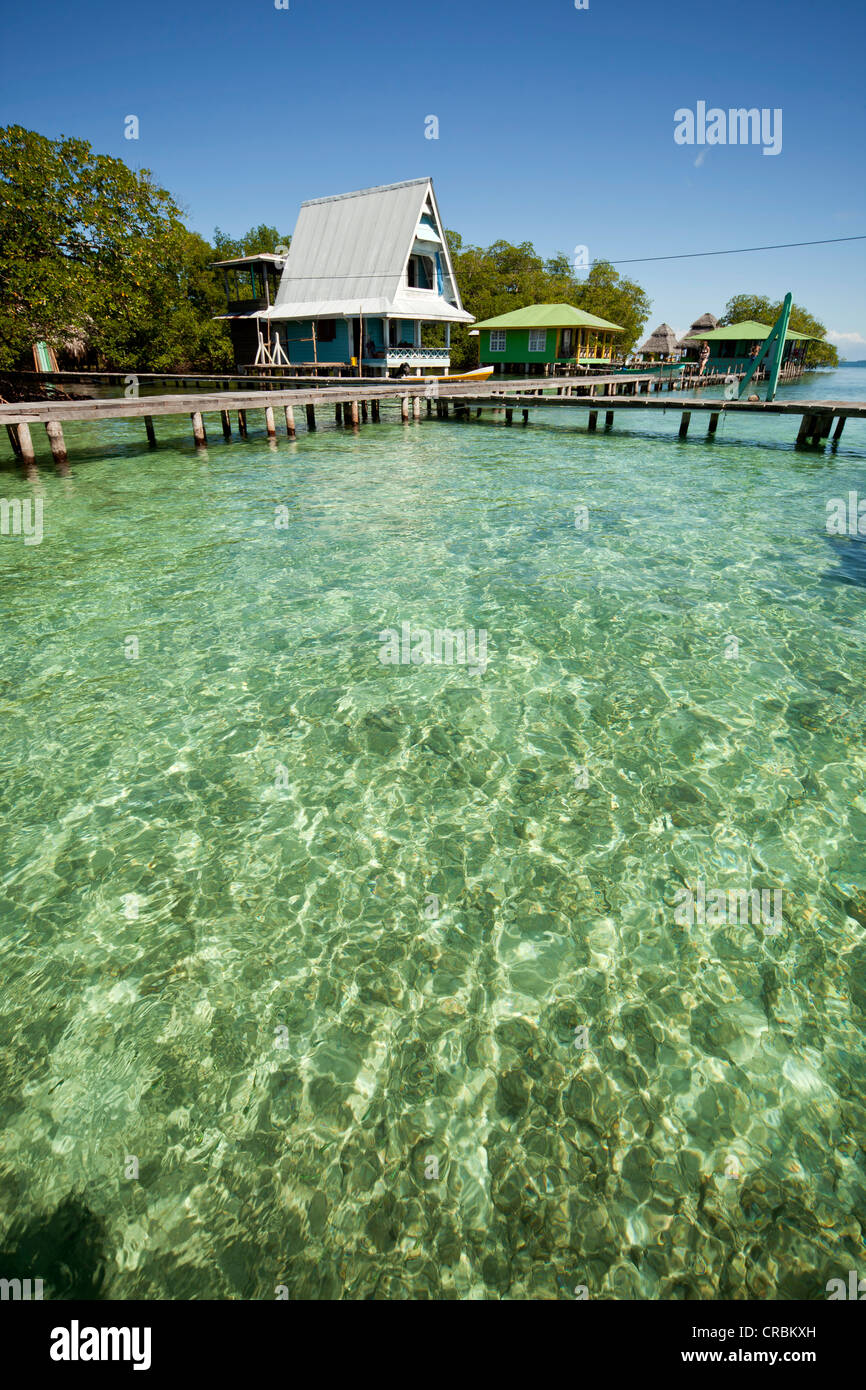 Jetty in the clear water and a typical wooden house on the small ...