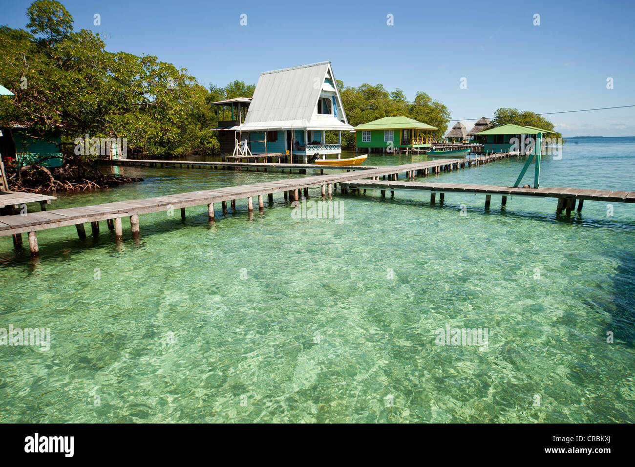 Jetty in the clear water and a typical wooden house on the small ...
