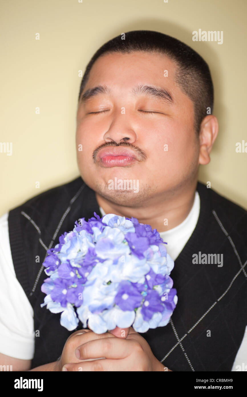 Funny man with eyes closed, smelling bunch of flowers Stock Photo - Alamy