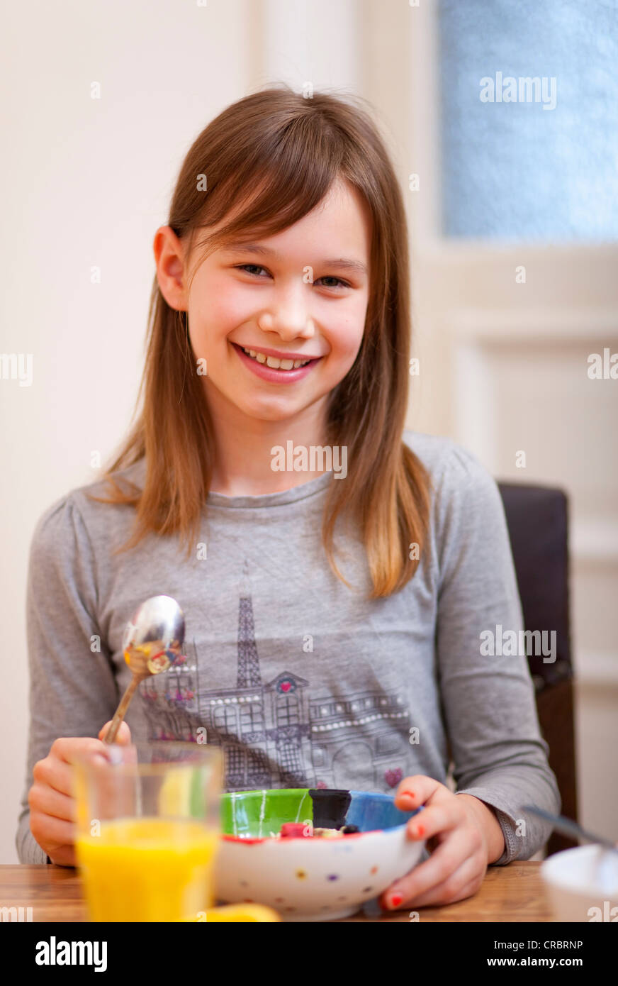 Smiling girl eating at table Stock Photo - Alamy