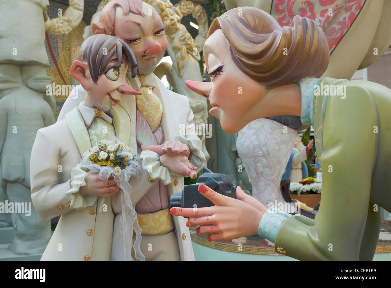 Crude carnival characters and satirical sculptures, woman filming a gay ...