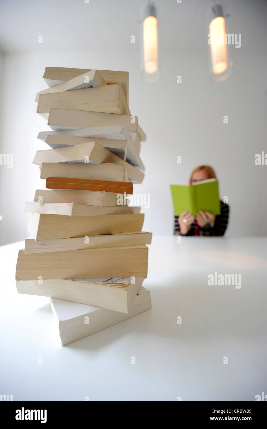 Stack of books in front of a reading woman Stock Photo - Alamy