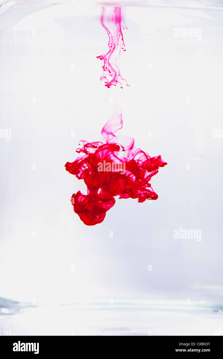 Red liquid dissolving in water Stock Photo - Alamy