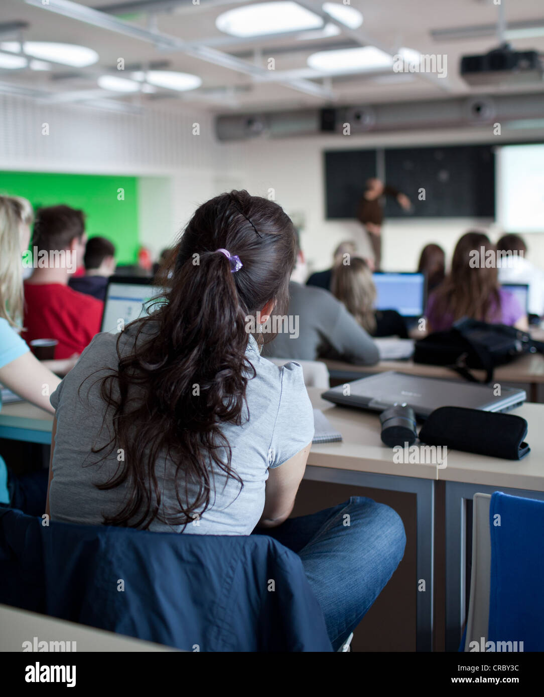 young pretty female college student sitting in a classroom full of ...
