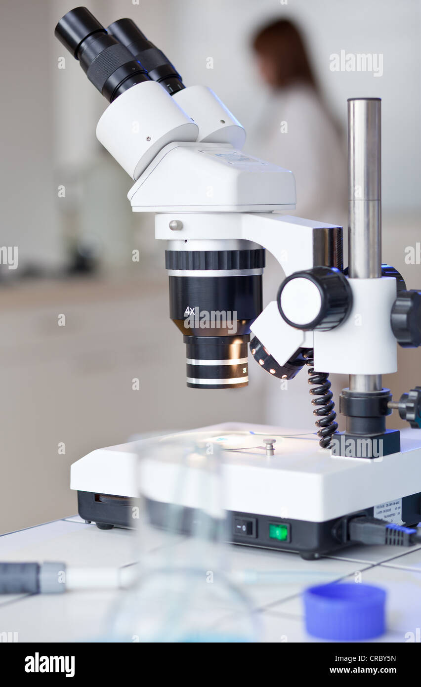 pretty female researcher using a microscope in a lab Stock Photo - Alamy