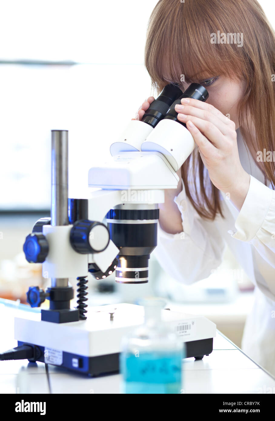 pretty female researcher using a microscope in a lab Stock Photo - Alamy