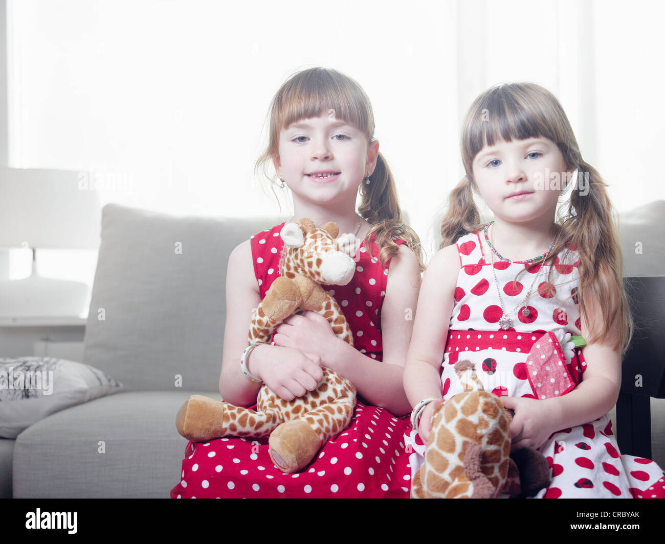 Girls holding stuffed animals on sofa Stock Photo - Alamy