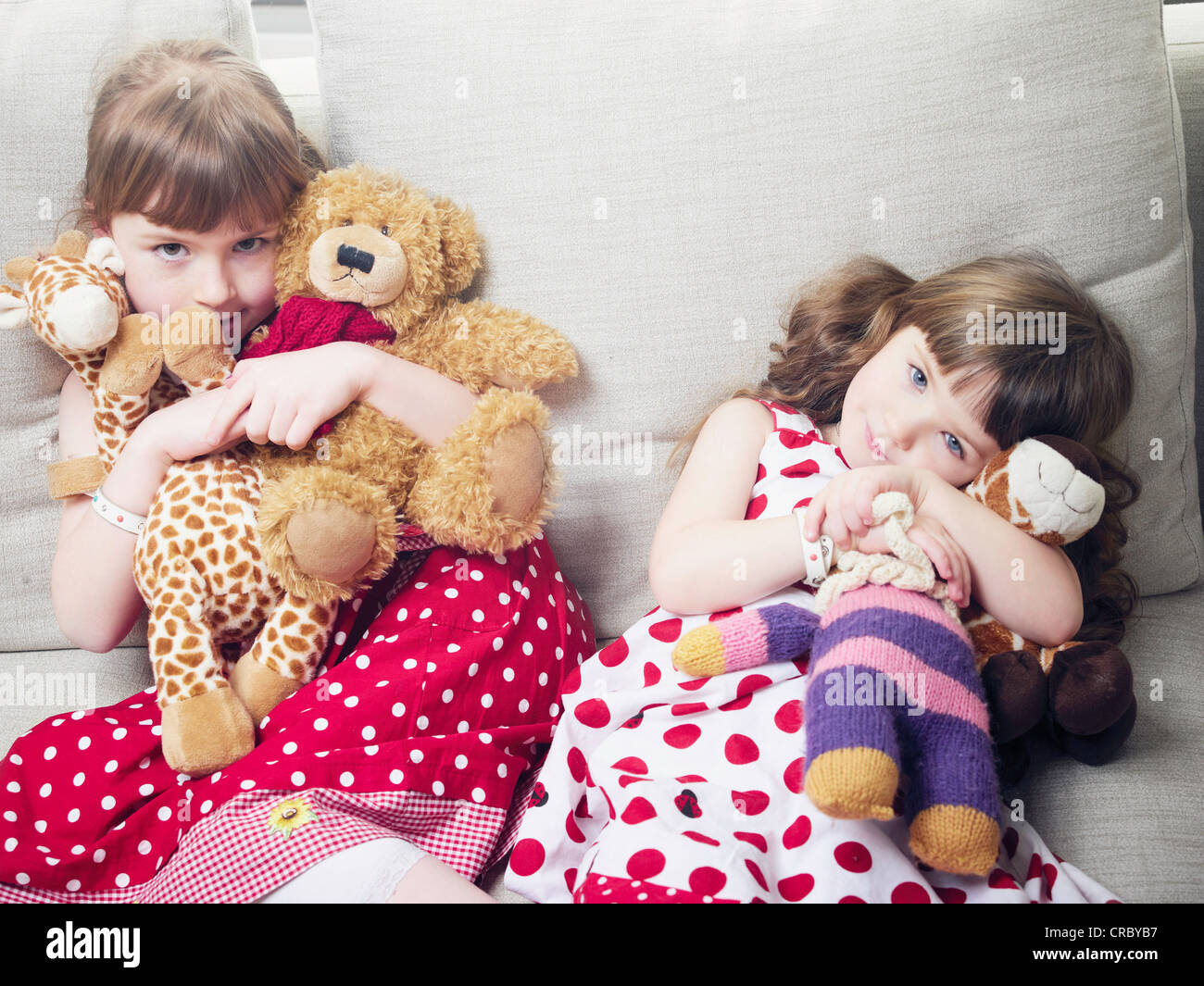 Girls holding stuffed animals on sofa Stock Photo - Alamy