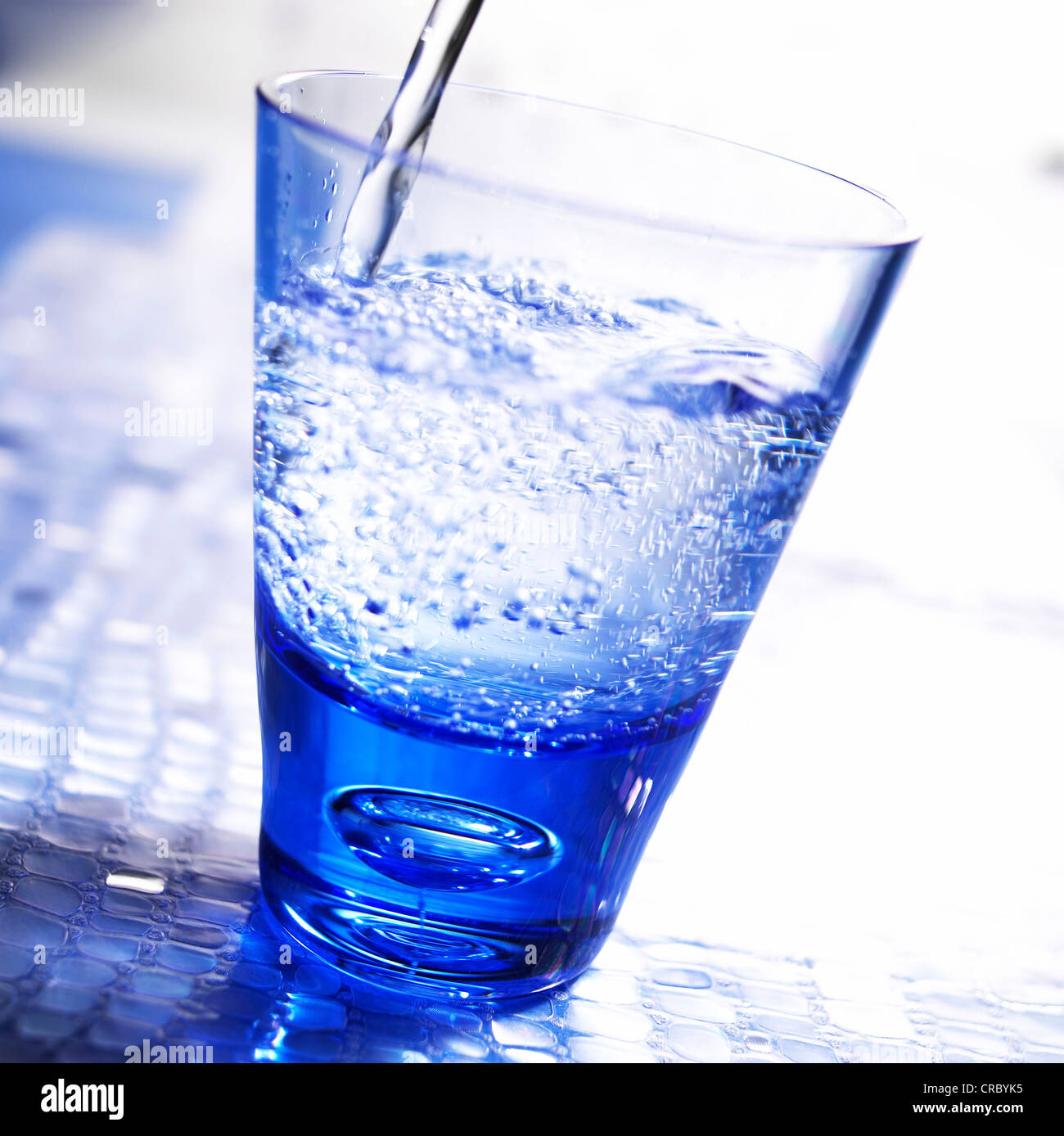 pouring water into a blue glass Stock Photo - Alamy