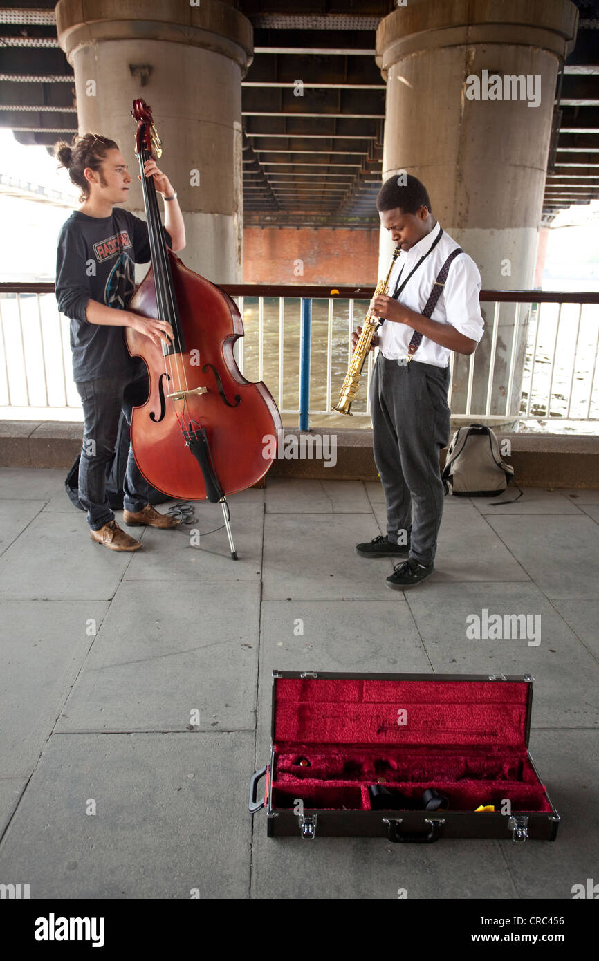 Full length portrait of two street buskers performing under a bridge ...