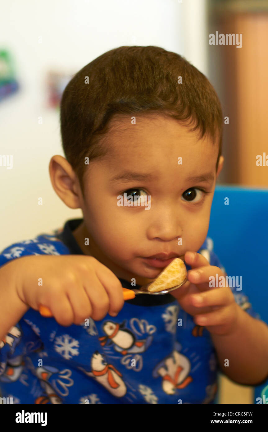 Boy eating fruit in kitchen Stock Photo - Alamy