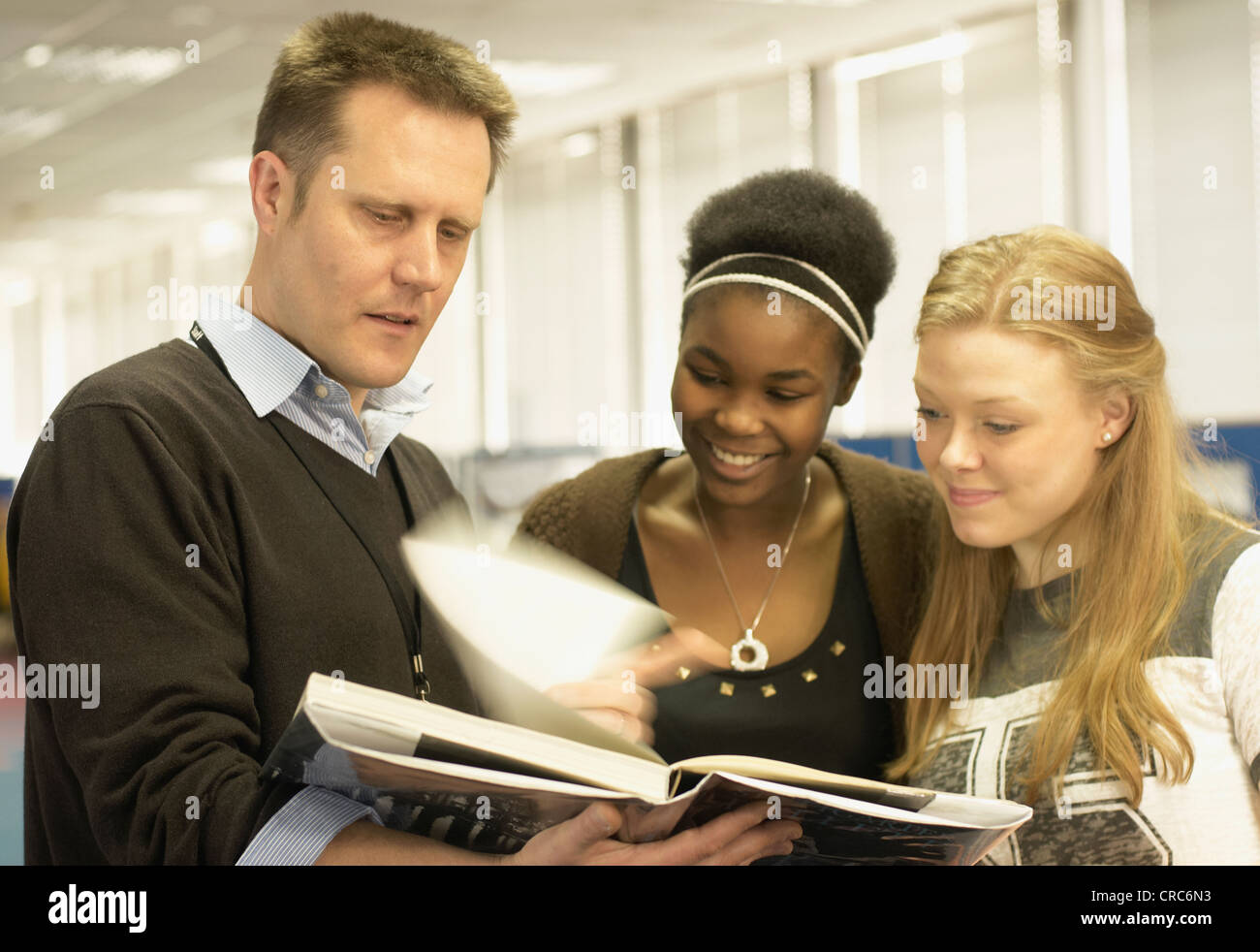 Students reading with teacher in library Stock Photo - Alamy