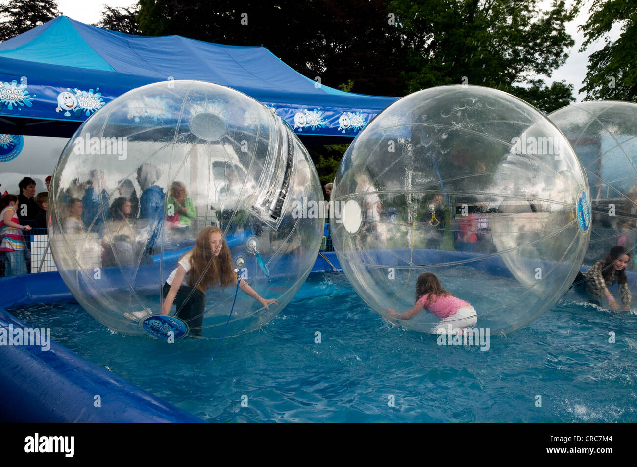 Young girls enjoying fun of the fair inside huge plastic bubbles during ...