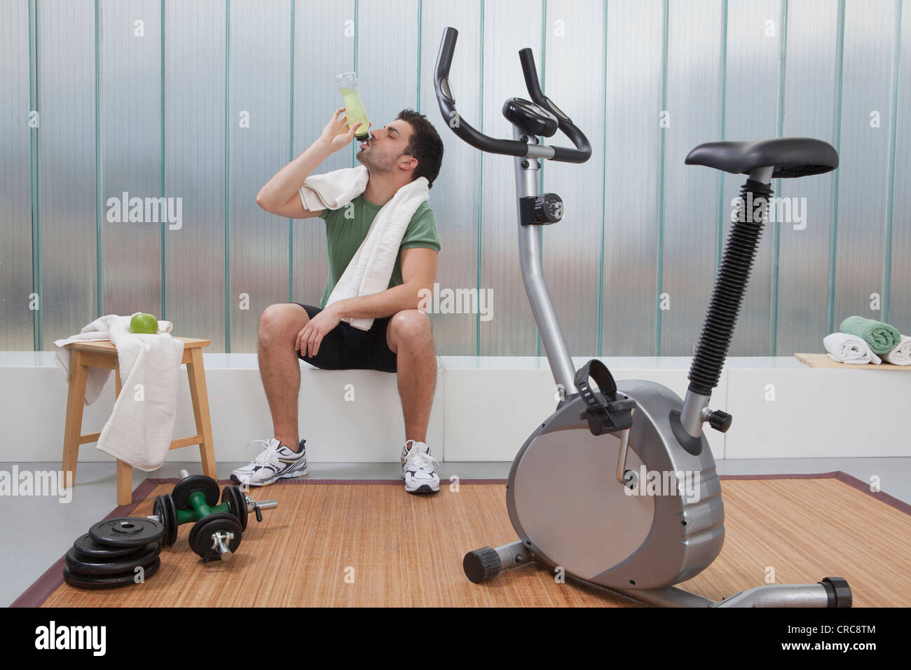 Man drinking sports drink in home gym Stock Photo - Alamy