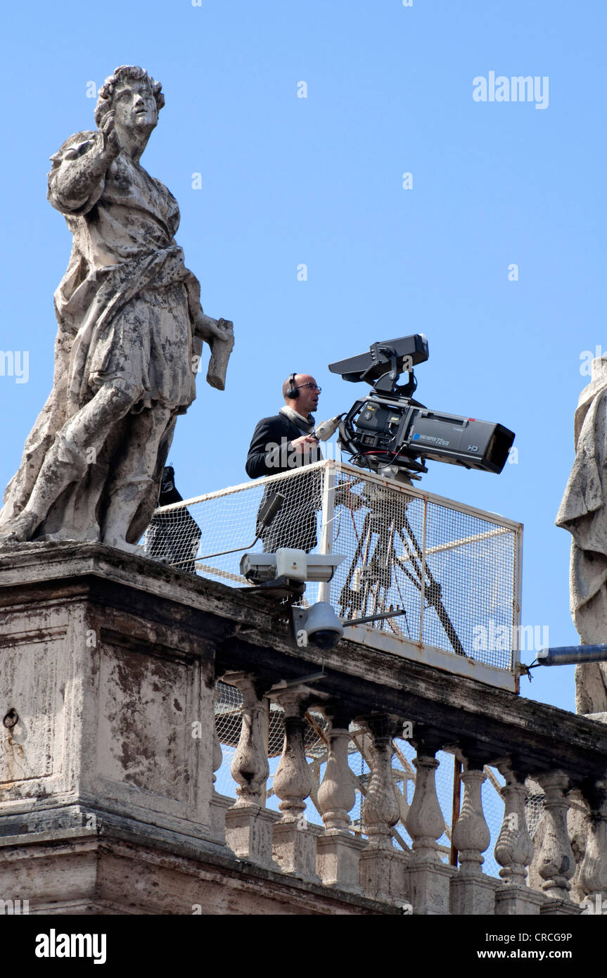 Cameraman operating a TV camera standing between monumental statues of ...