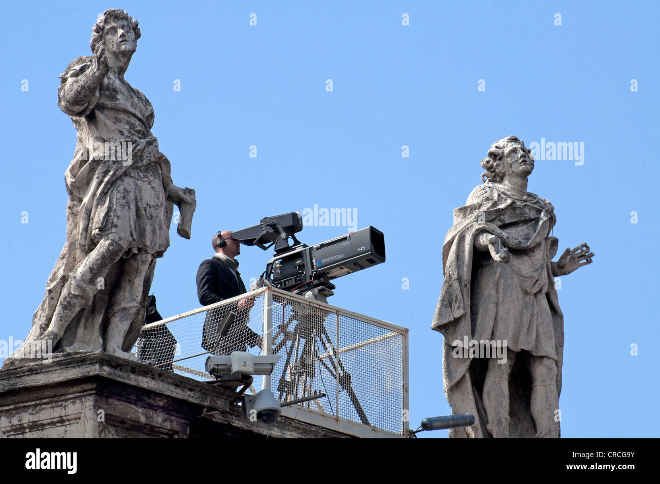 Cameraman operating a TV camera standing between monumental statues of ...