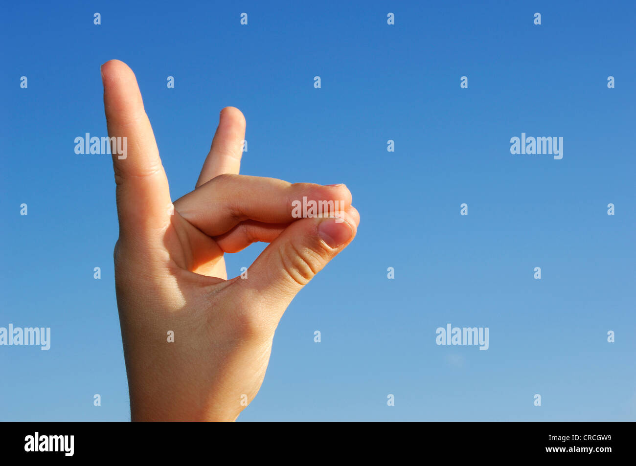 hand making sign in front of blue sky Stock Photo - Alamy