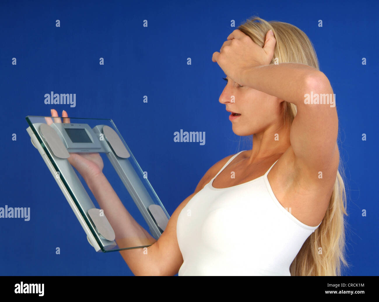 shocked blond woman looking at the scale in her hand Stock Photo - Alamy