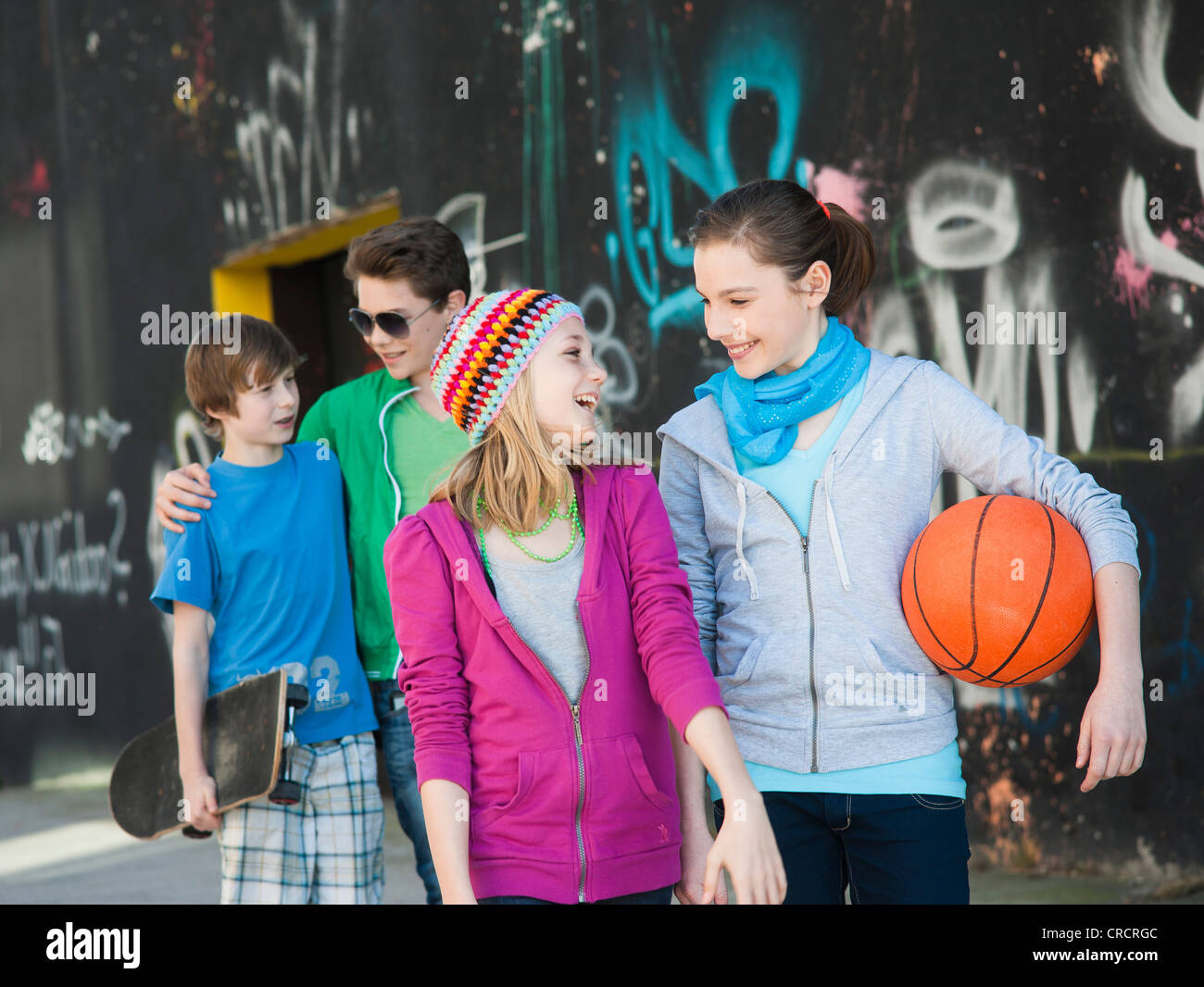 Four happy teenage friends walking at graffiti wall Stock Photo - Alamy