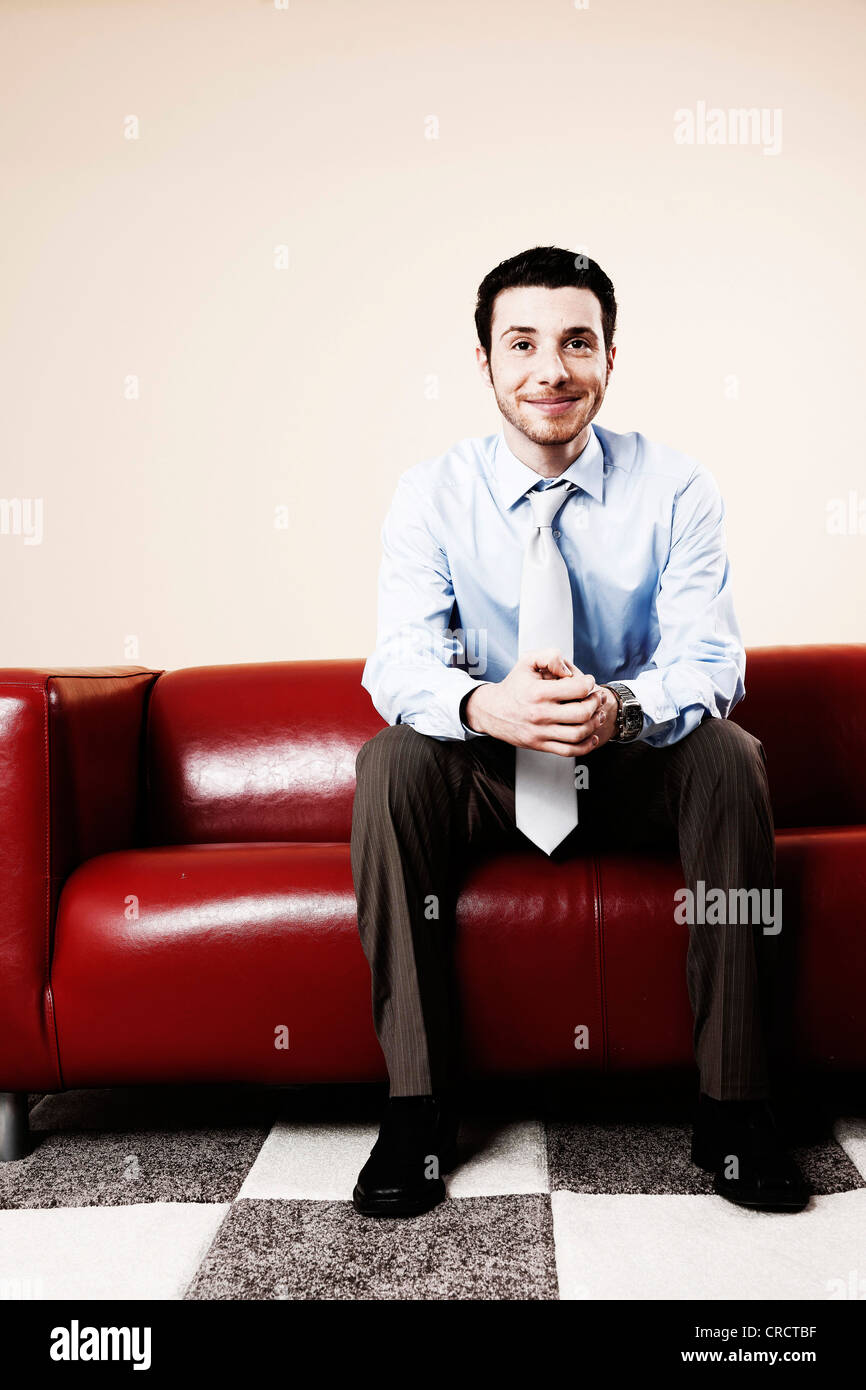 Young man sitting on sofa Stock Photo - Alamy