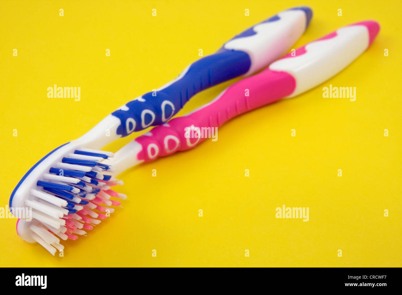 Two colorful tooth-brushes on a yellow background Stock Photo - Alamy