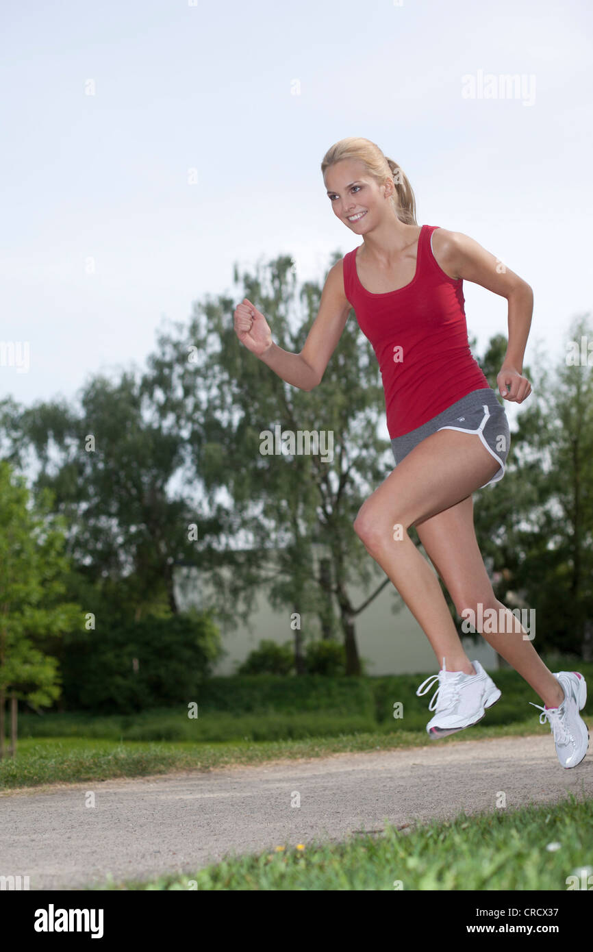 Blond young woman running on path Stock Photo - Alamy