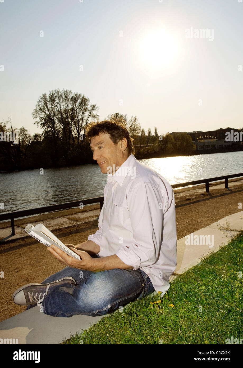 Man reading book on the waterfront Stock Photo - Alamy