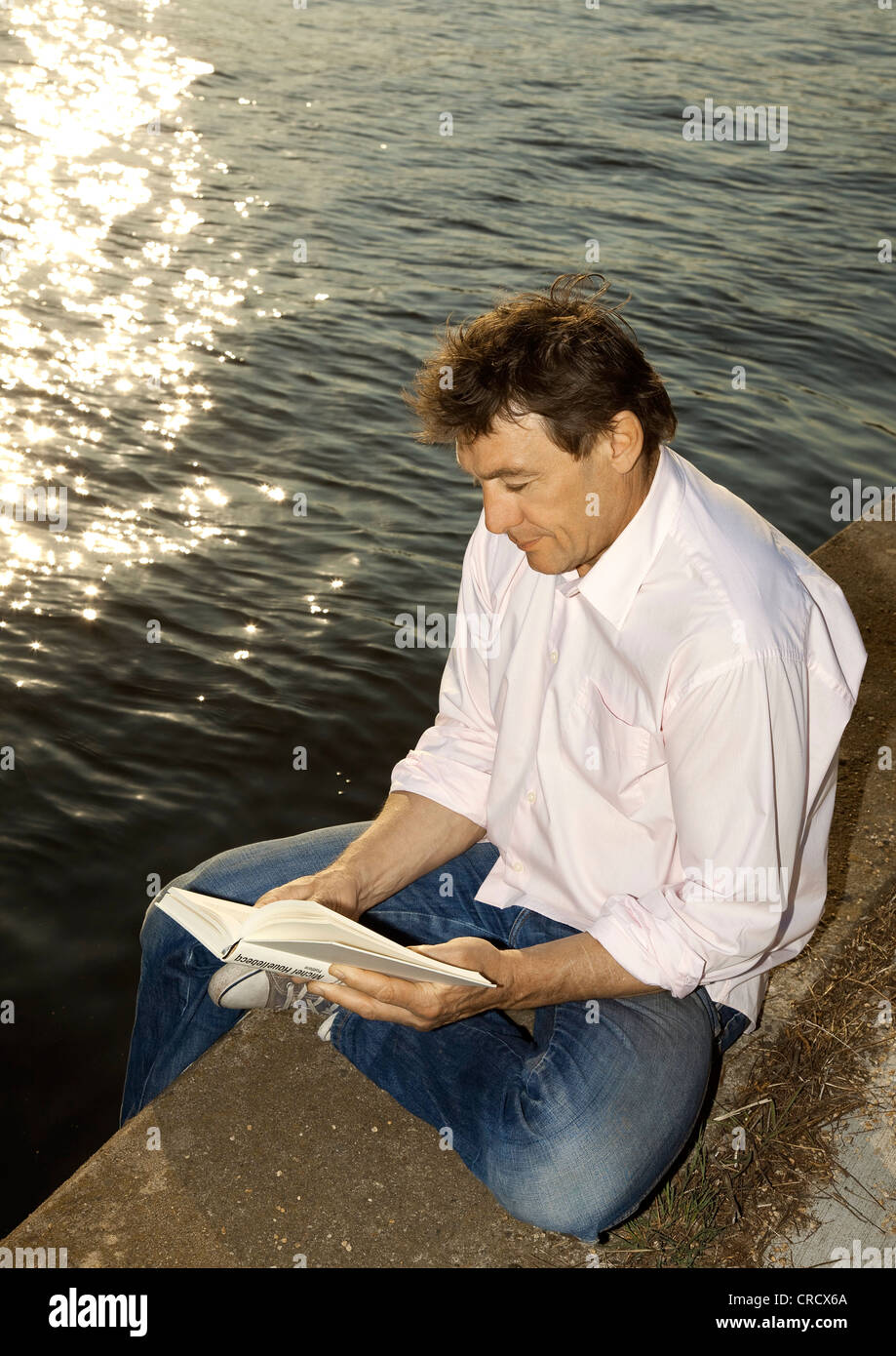 Man reading book on the waterfront Stock Photo - Alamy