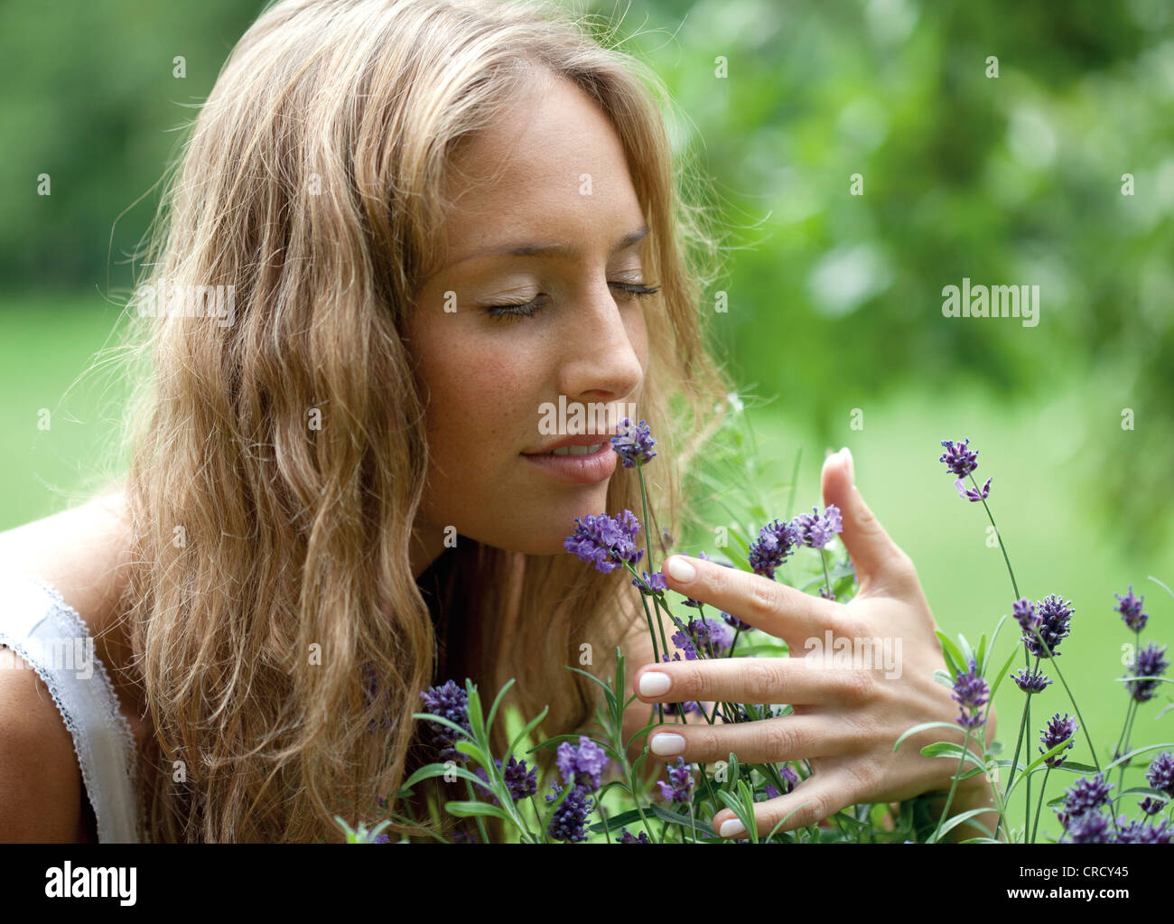 Young woman smelling at flowers Stock Photo - Alamy