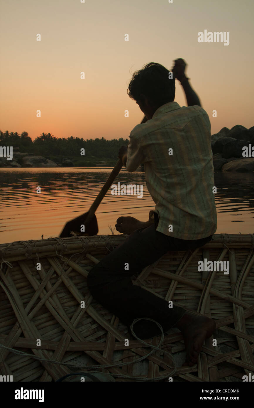 Boy rowing a coracle reed boat - Hampi, India at Sunset Stock Photo - Alamy