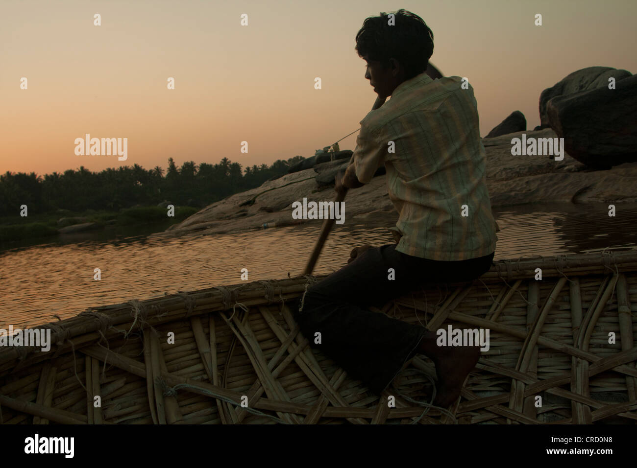 Boy rowing a coracle reed boat - Hampi, India at Sunset Stock Photo - Alamy