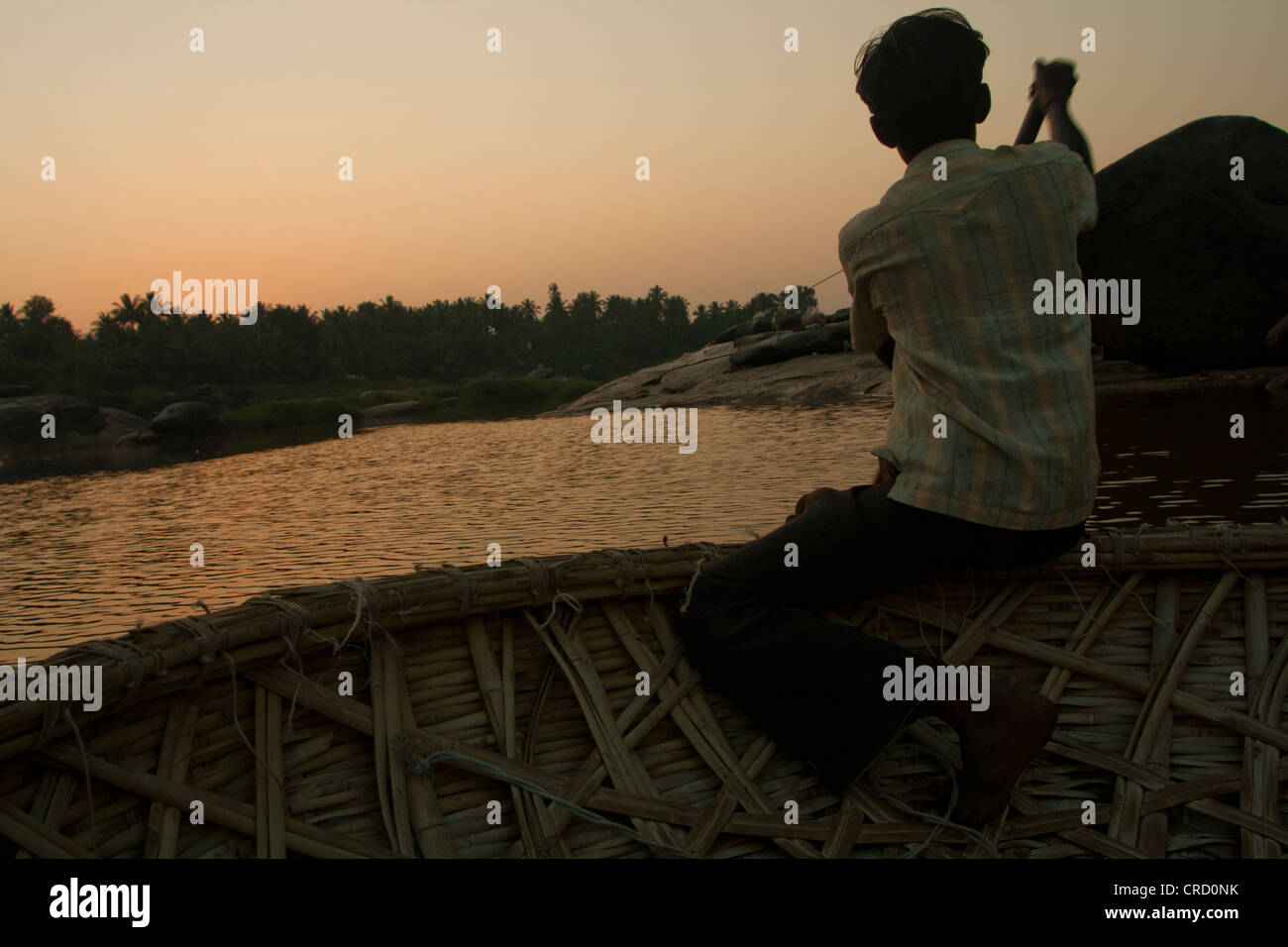 Boy rowing a coracle reed boat - Hampi, India at Sunset Stock Photo - Alamy