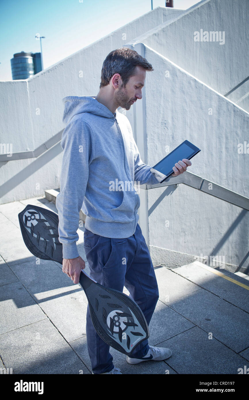 Man with ipad and waveboard outdoors Stock Photo - Alamy