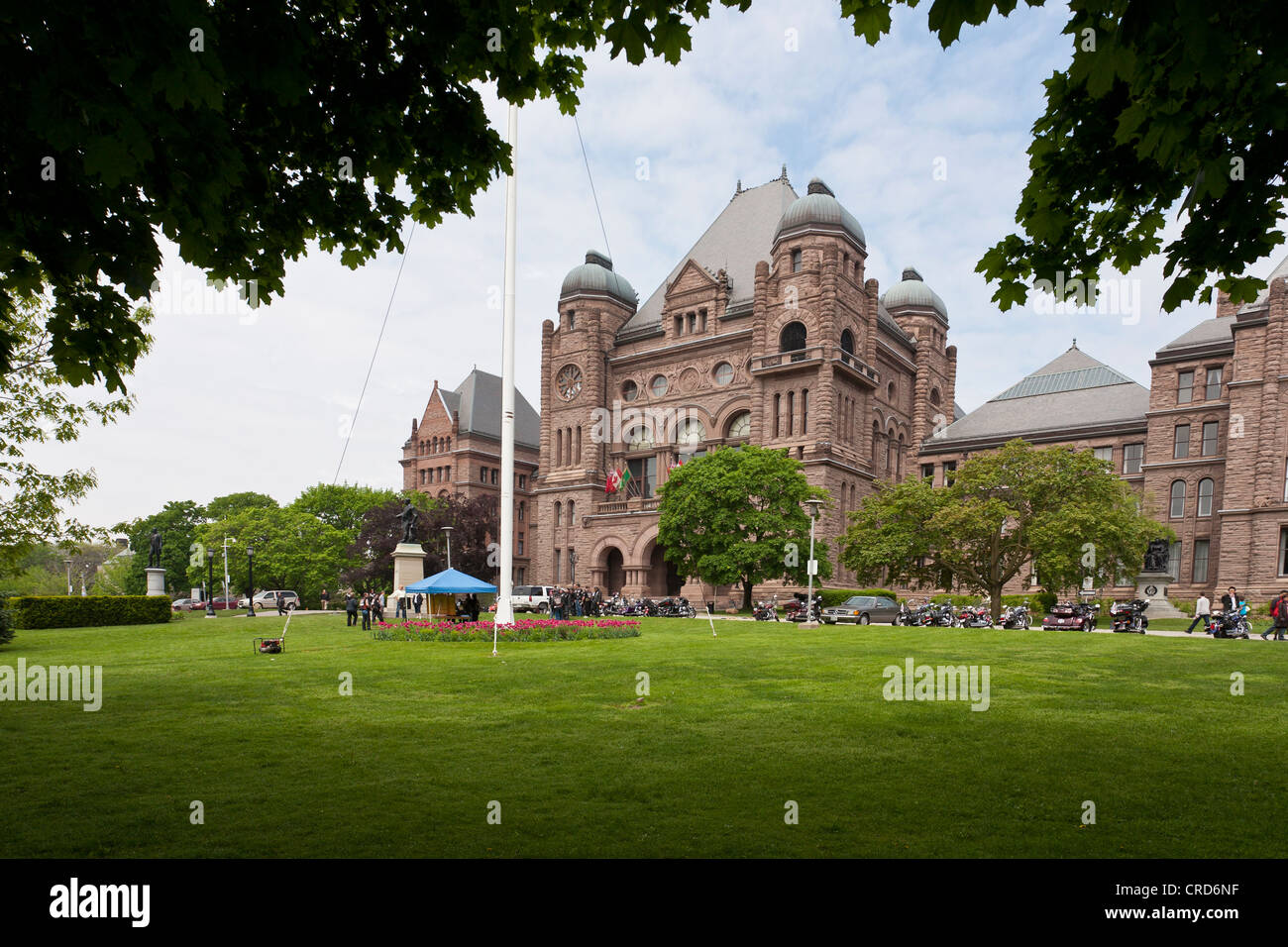 A maple leaf framed Ontario Legislature Building. Green lawns anchor ...