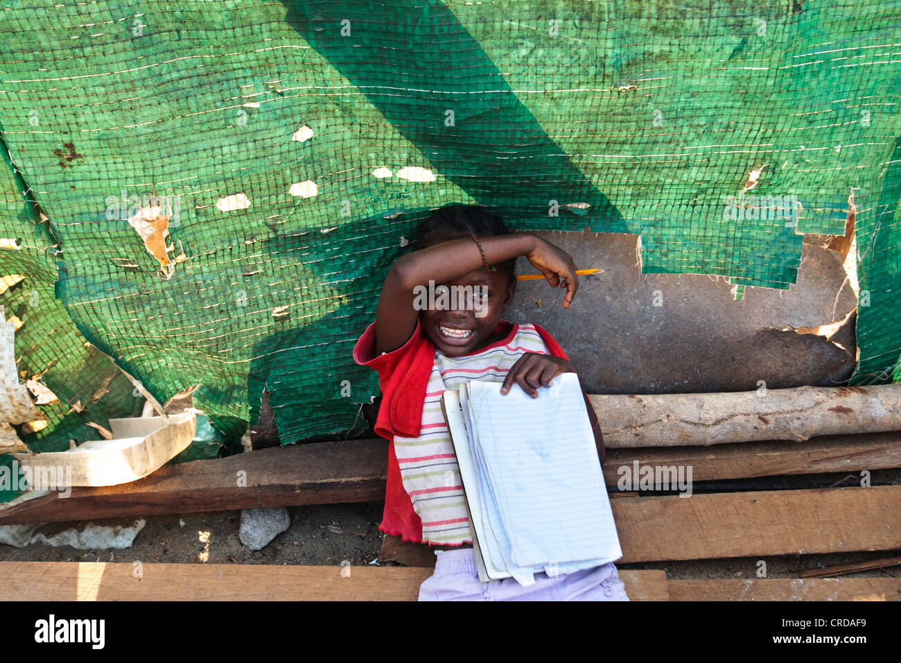 A girl laughs while doing her homework in the West Point slum of ...